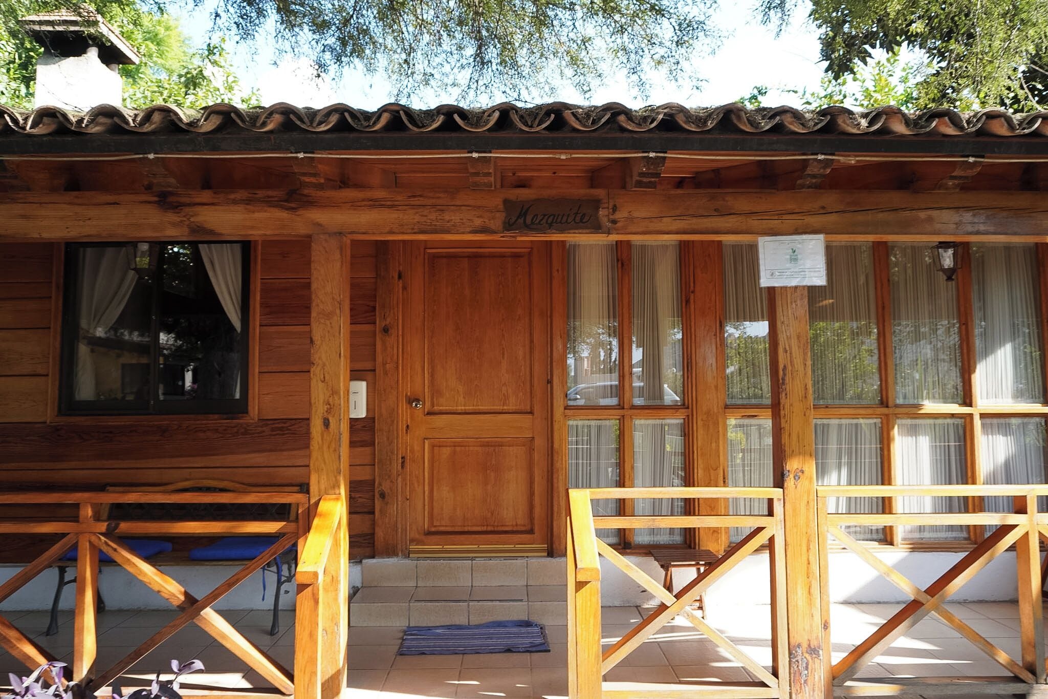 Uma cabana de madeira com porta de madeira, uma janela e um pequeno alpendre.