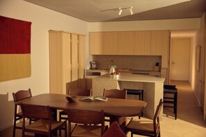 Uma cozinha compacta com uma ilha central, armários de madeira e uma área de refeições com mesa e cadeiras.