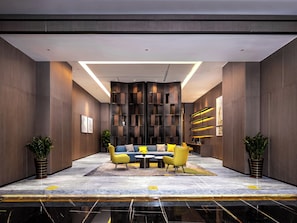 Um hall moderno com área de estar central, parede decorativa e chão de mármore.