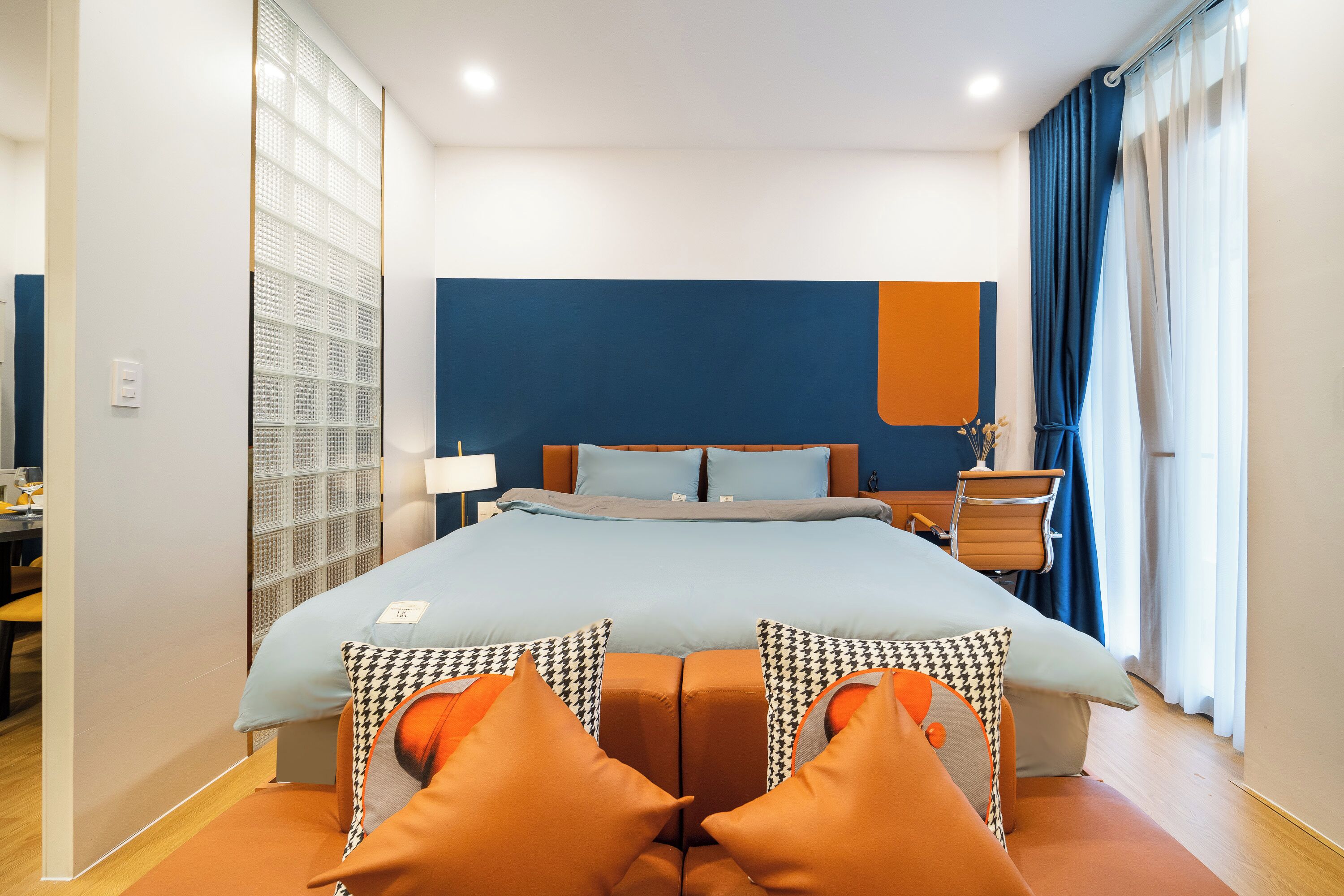 Quarto moderno com cama grande, mesa de cabeceira e uma cadeira.