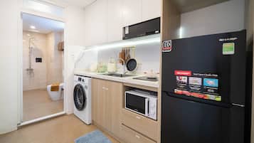 Cozinha compacta com máquina de lavar, micro-ondas e geladeira preta.