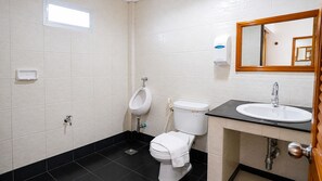 Casa de banho com urinol, sanita, lavatório e espelho.