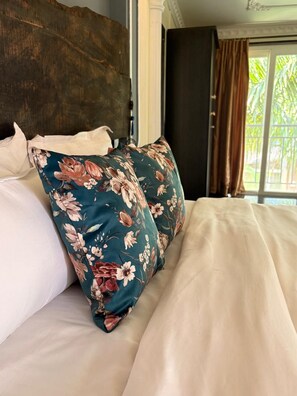 Uma cama com almofadas florais e um edredom branco.
