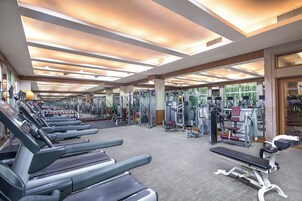 Uma academia com esteiras, aparelhos de musculação e espelhos.