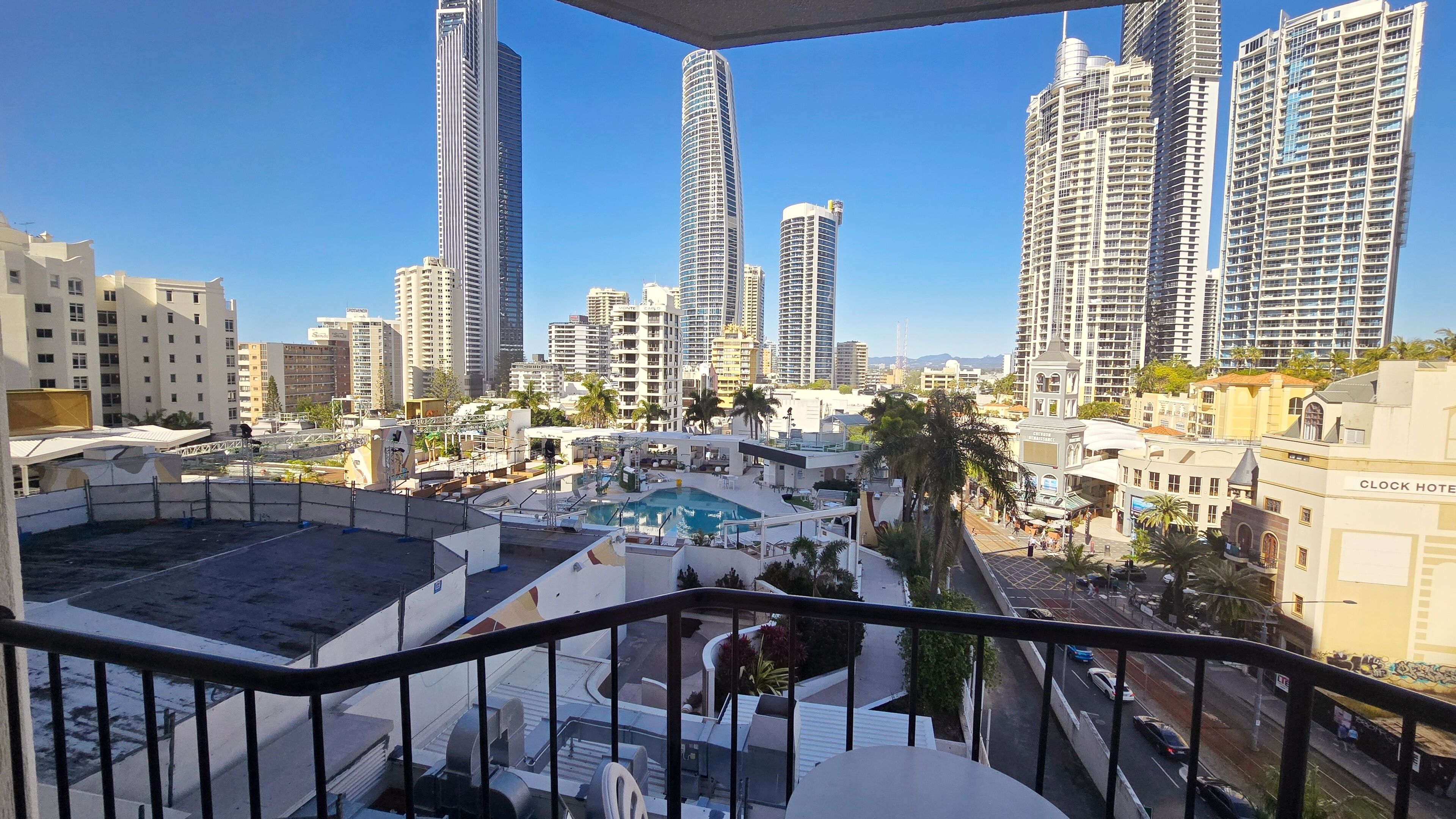 Um edifício alto com área de piscina, rodeado por outros edifícios imponentes.