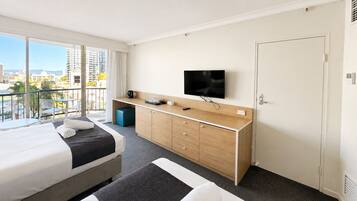 Quarto de hotel com uma cama, televisão, minibar e vista para a cidade.
