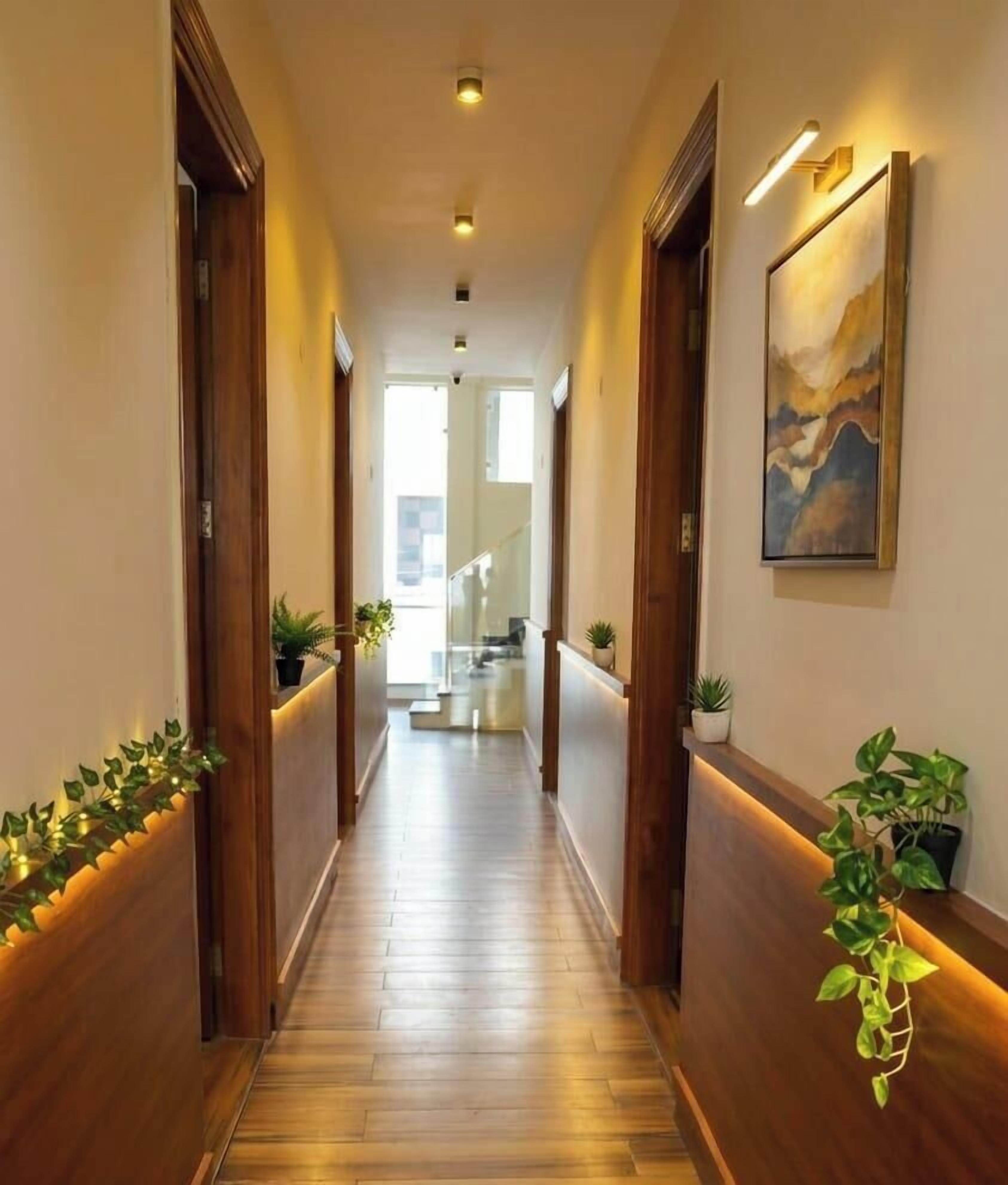 Um corredor com piso de madeira, plantas em vasos e iluminação embutida.