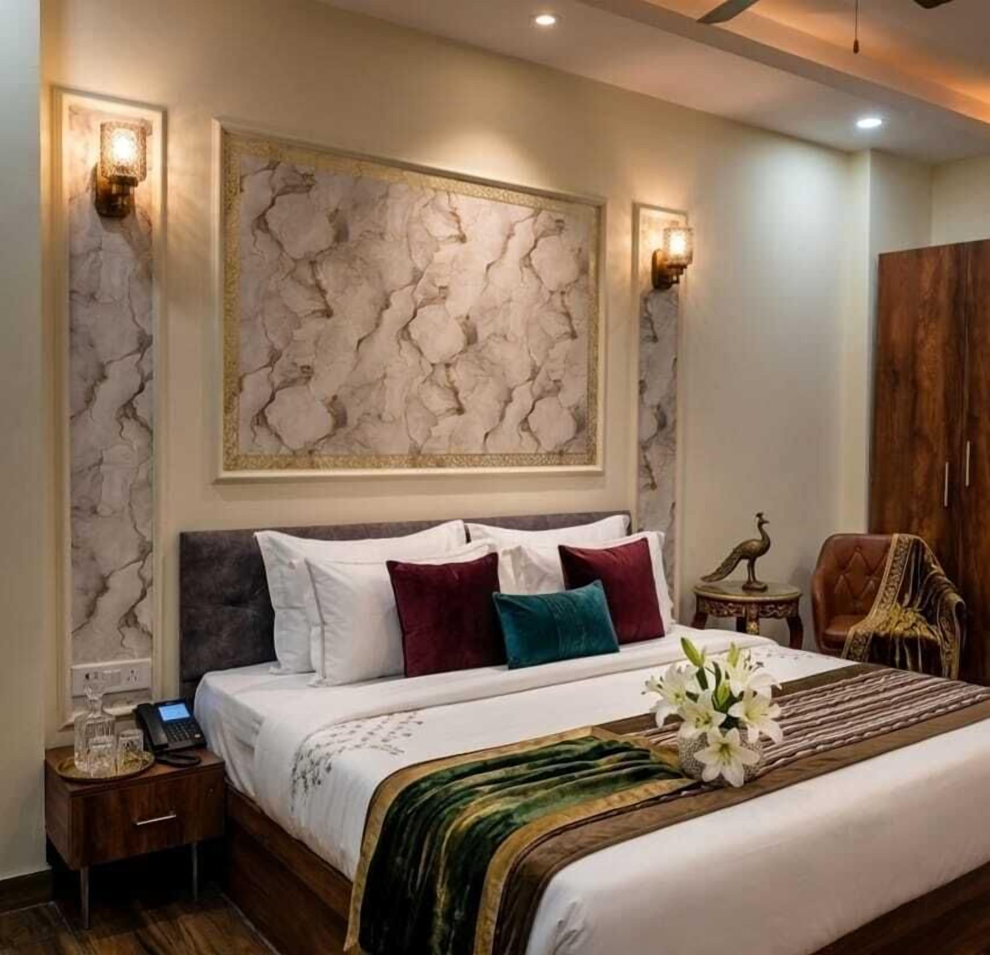 Quarto com cama grande, mesa de cabeceira, painel decorativo na parede e guarda-roupa de madeira.