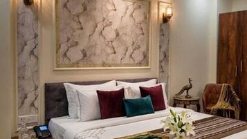 Quarto com cama grande, mesa de cabeceira, painel decorativo na parede e guarda-roupa de madeira.
