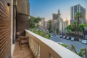 Uma varanda com vista para um horizonte urbano, incluindo um edifício com cúpula e guindastes de construção.