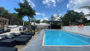 Uma piscina com espreguiçadeiras e área coberta.