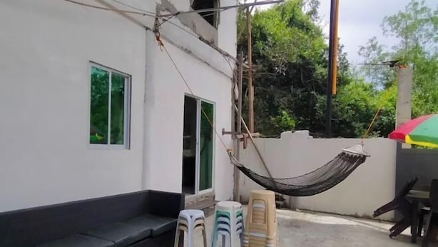 Um pátio com uma rede, área de estar externa e uma pequena mesa.