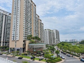 Um edifício residencial alto com várias varandas, uma cafeteria Starbucks e uma rua urbana bem cuidada, com carros e vegetação.