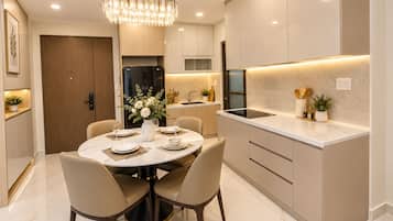 Cozinha moderna com mesa de jantar redonda, cadeiras bege, lustre e micro-ondas embutido.