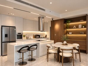 Cozinha moderna com ilha central, banquetas de bar, mesa de jantar redonda e prateleiras de madeira embutidas.