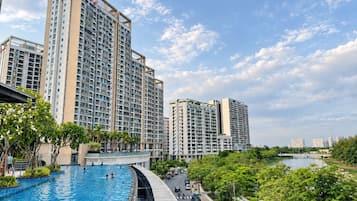 Um edifício moderno e imponente com piscina, rodeado por vegetação e um céu claro.