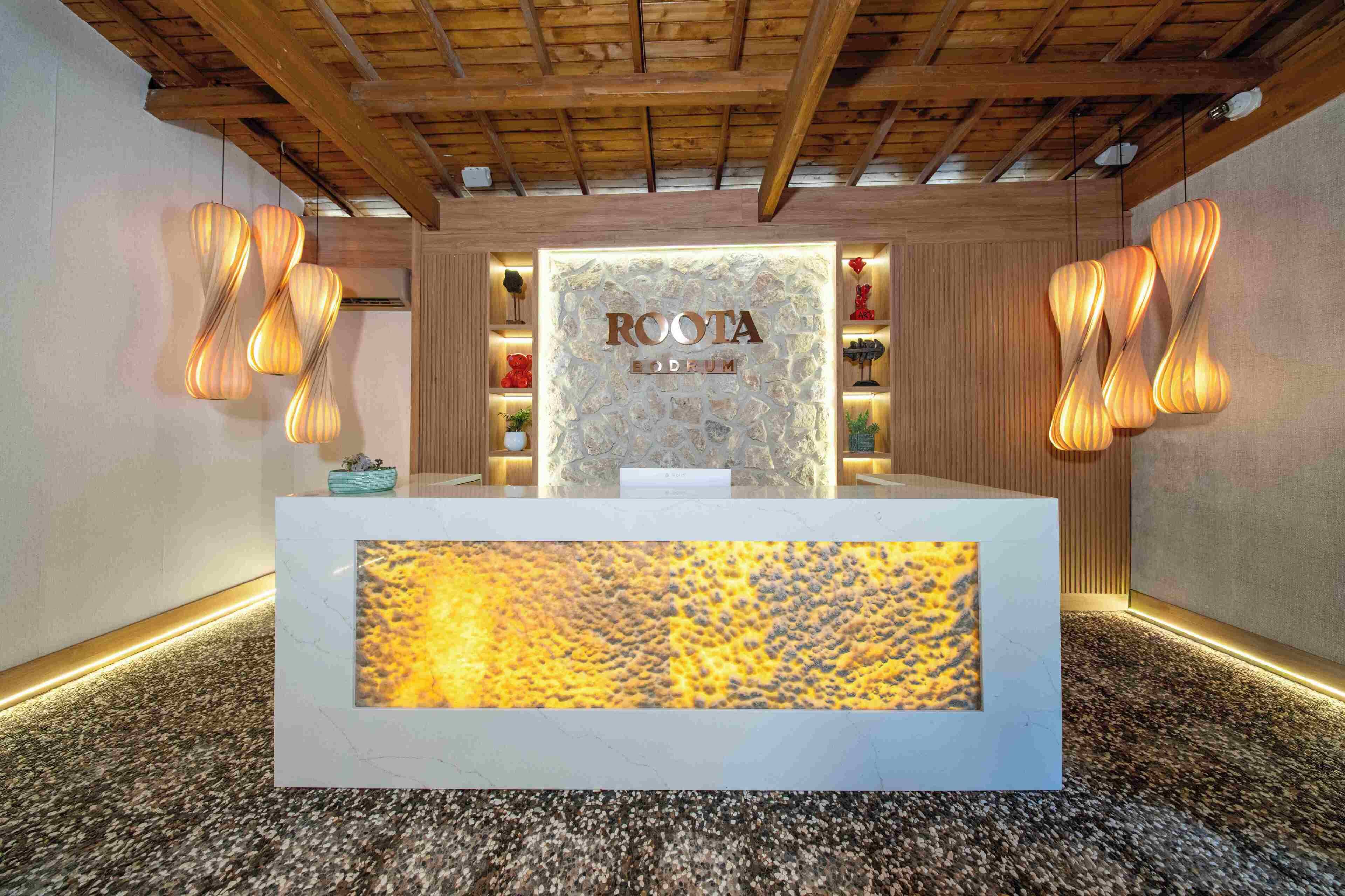A reception desk with a stone wall backdrop, wooden beams, and wall-mounted lamps.