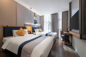 Quarto de hotel com duas camas, uma escrivaninha, televisão e uma janela grande com cortinas.