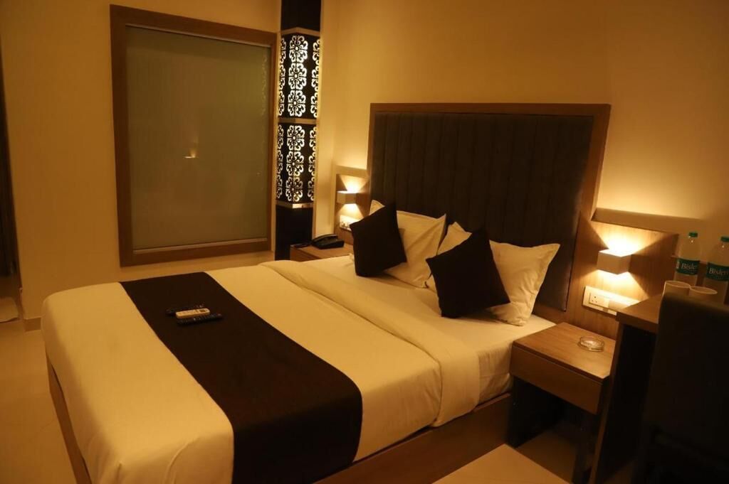 Quarto de hotel com uma cama grande, mesas de cabeceira, um criado-mudo, um controle remoto e uma janela com vista.