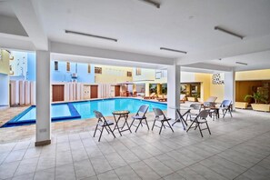 Uma área de piscina com espreguiçadeiras e um espaço de estar coberto.