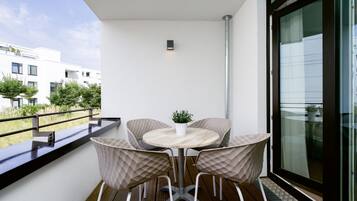 Varanda com mesa e cadeiras, um vaso de planta e vista para edifícios.