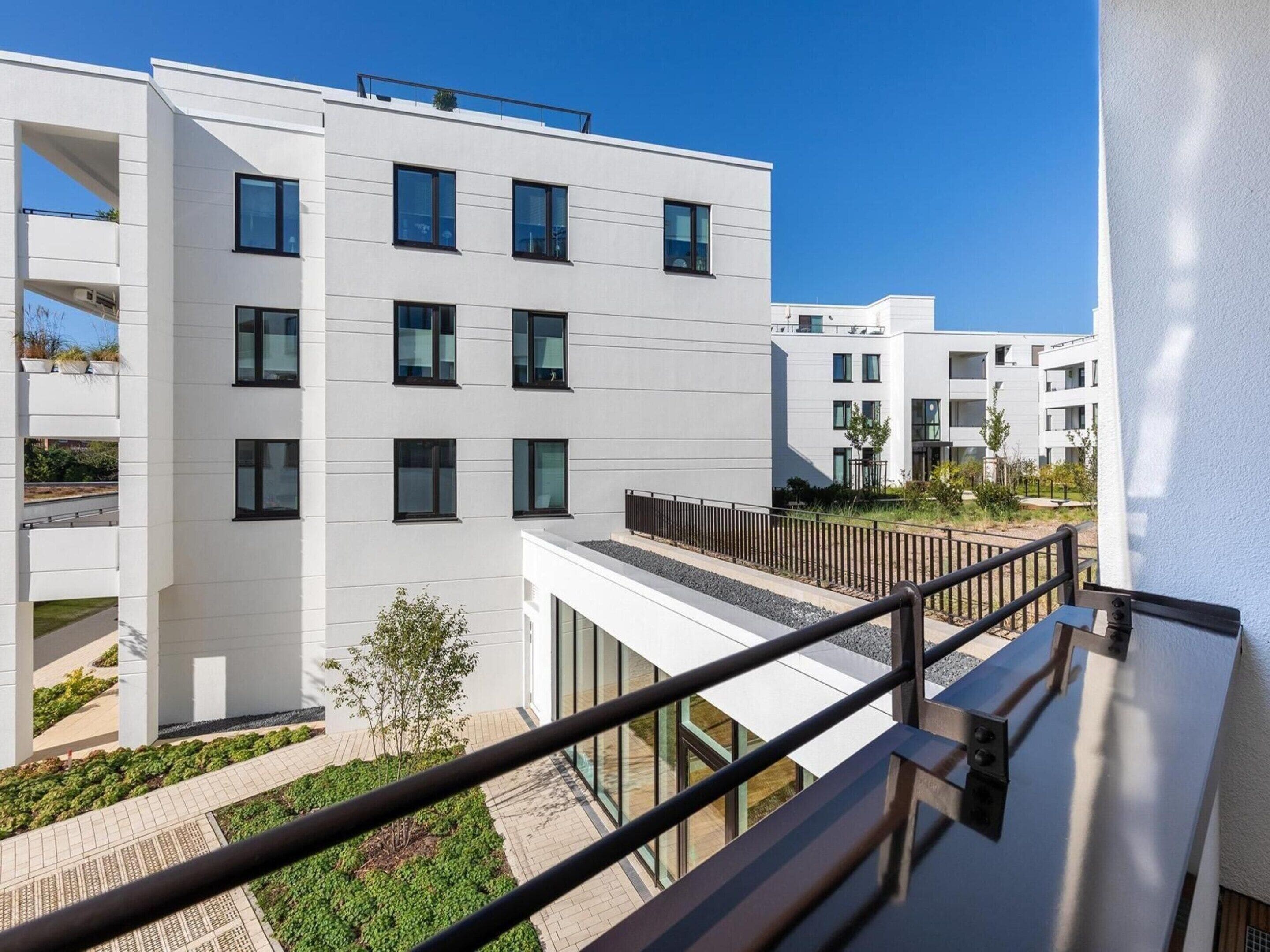 Um edifício residencial moderno com várias varandas e céu claro.