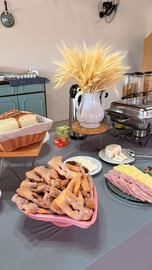 Uma mesa de buffet com pães, doces, queijo e presunto.
