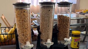 Três distribuidores de comida com conteúdos distintos sobre uma mesa.