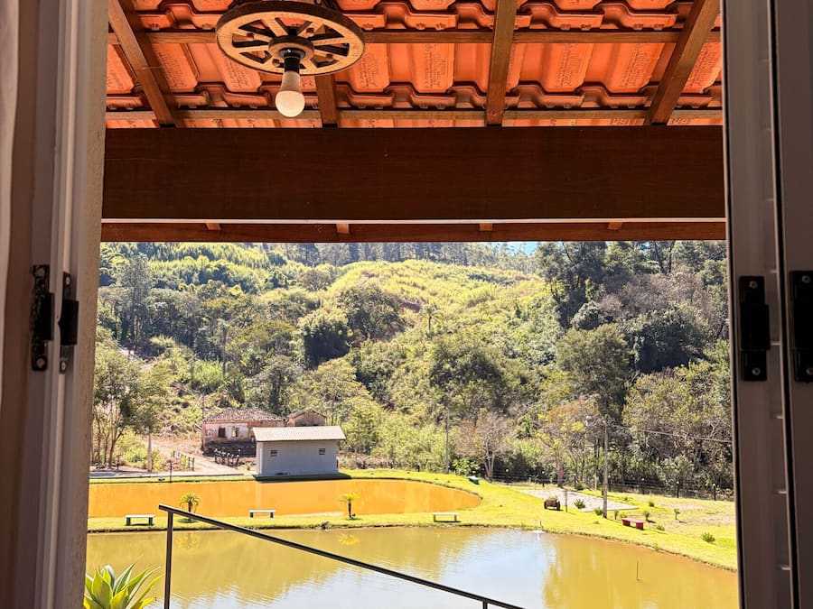Visão através de uma porta, revelando um edifício com teto de madeira e luminária pendente.