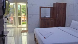 Um quarto com uma cama, um guarda-roupa de madeira, um espelho e uma televisão.