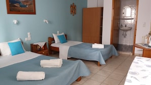 A hotel room with two beds, a wooden wardrobe, a bathroom with a sink, and a painting on the wall.