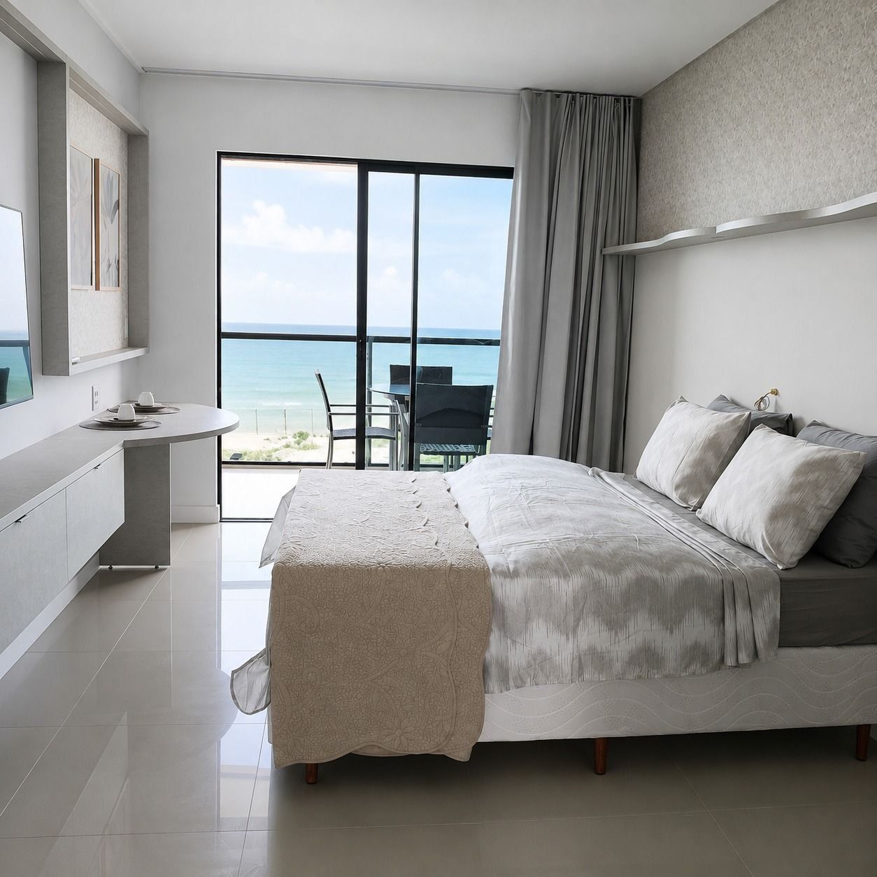 Quarto moderno com uma cama grande, uma escrivaninha e vista para o oceano.