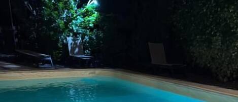 Piscina com borda curva, rodeada por um deck revestido de azulejos.