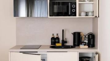 Cozinha compacta com micro-ondas, cafeteira e pequena geladeira.