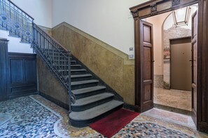 Uma escada com corrimão, tapete vermelho e piso estampado.