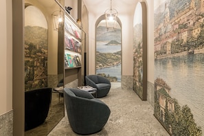 Corredor com um mural, área de estar e estante de livros.