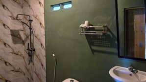 Casa de banho com sanita, lavatório e chuveiro.