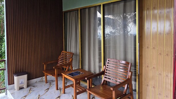 Uma área de estar coberta ao ar livre, com móveis de madeira e chão de azulejos.