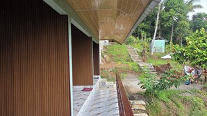 Teto de madeira com claraboia, chão de mármore com tapete de entrada e vista para um jardim com escadaria.