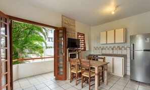 Cozinha compacta com área de refeições, televisão e geladeira.