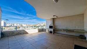 Uma área de cozinha externa com forno de tijolos, pia e vista para o horizonte da cidade.
