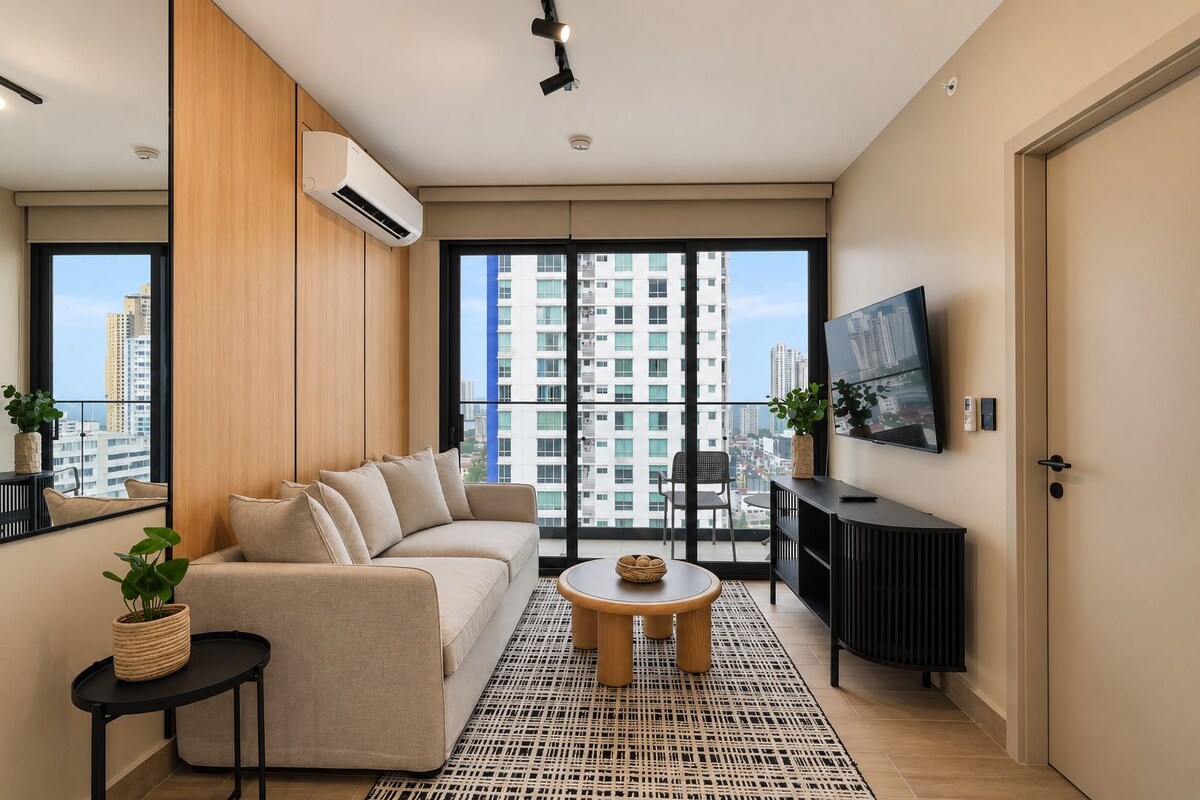Uma sala de estar moderna com um sofá, uma mesa de centro e uma TV na parede.