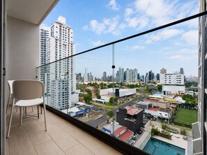 Uma varanda com vista para a cidade, uma cadeira e uma área de piscina.