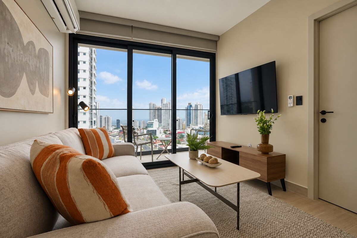 Uma sala de estar moderna com sofá, mesa de centro e TV fixada na parede.