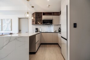 Cozinha moderna com bancada de mármore, armários embutidos e uma ilha central.
