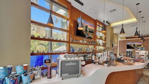 Uma área de bar com balcão, prateleiras com garrafas e uma máquina de café.