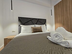Quarto de hotel com uma cama, um guarda-roupa de madeira e uma mesa de cabeceira.