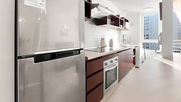 Cozinha moderna com eletrodomésticos de aço inoxidável, armários de madeira e uma grande janela com vista para a paisagem urbana.