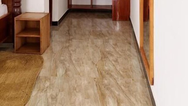 Um corredor com uma porta de madeira, um banquinho de madeira e um tapete no chão.
