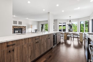 A modern kitchen with a large island, wooden cabinets, and a built-in fireplace.